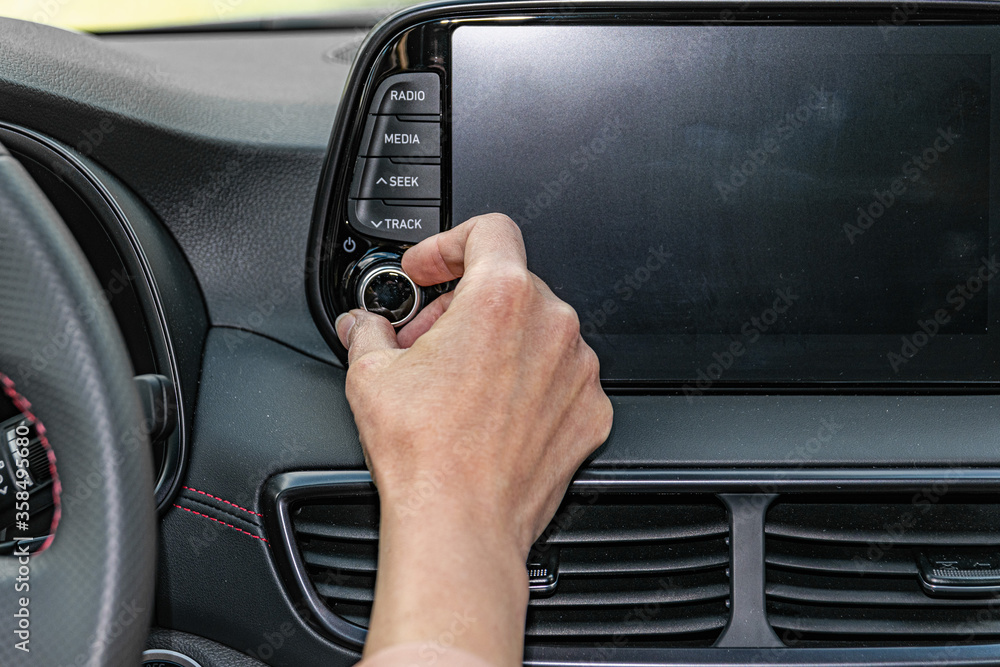 Closeup of woman hand, turning button on car radio for listening to ...