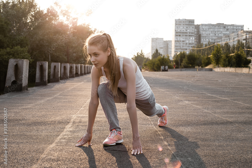Girl stretching her legs outdoor and preparing to sport trainings ...