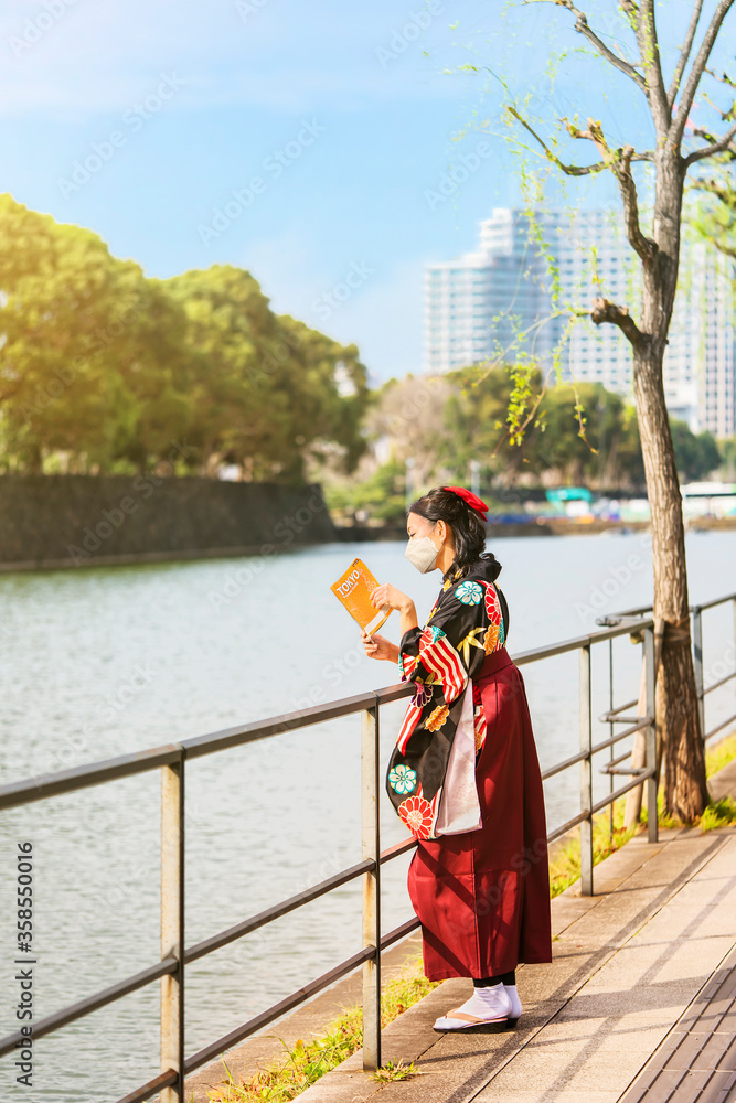 Japanese woman dressed in a hakama kimono and wearing a facial mask ...