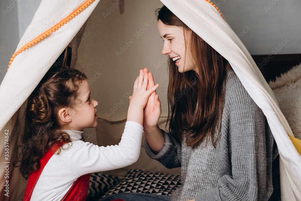 Cheerful mom and cute kid daughter playing patty cake at home, carefree ...