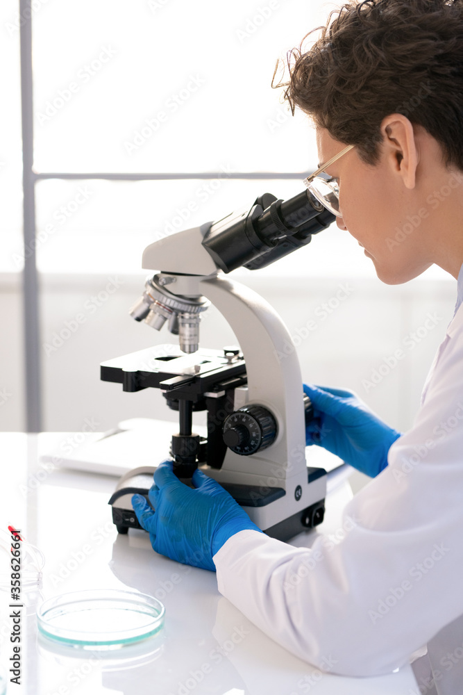 Over shoulder view of concentrated lab researcher using microscope ...