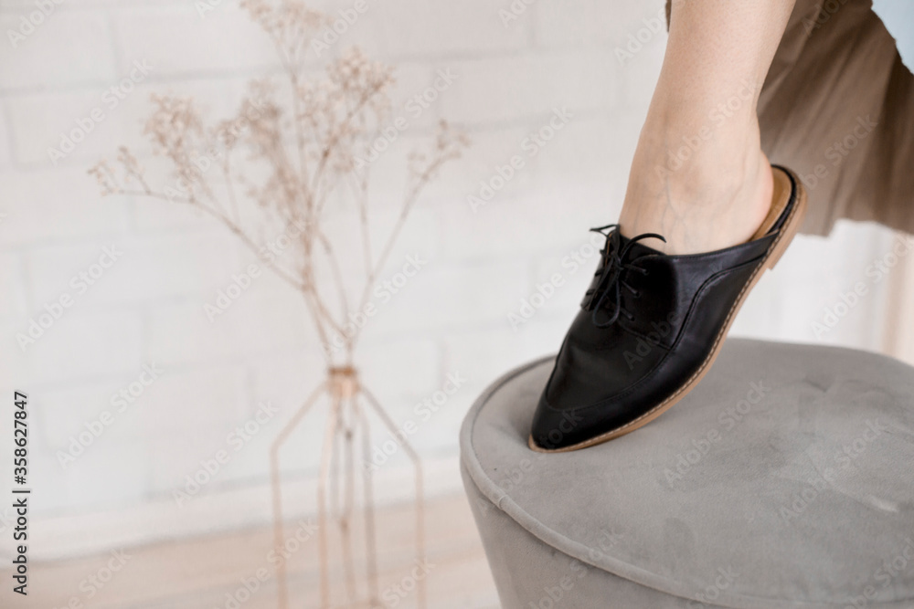 girl takes off her office shoes in a room in bed on white bedding, is ...