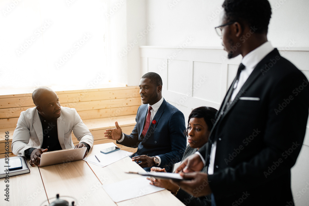 A black company representative in a black suit makes a presentation to ...