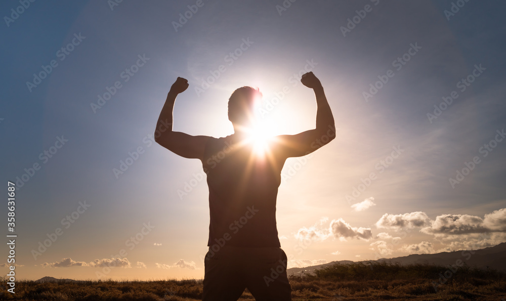Strong man flexing arms facing sunset sky. People power and strength ...