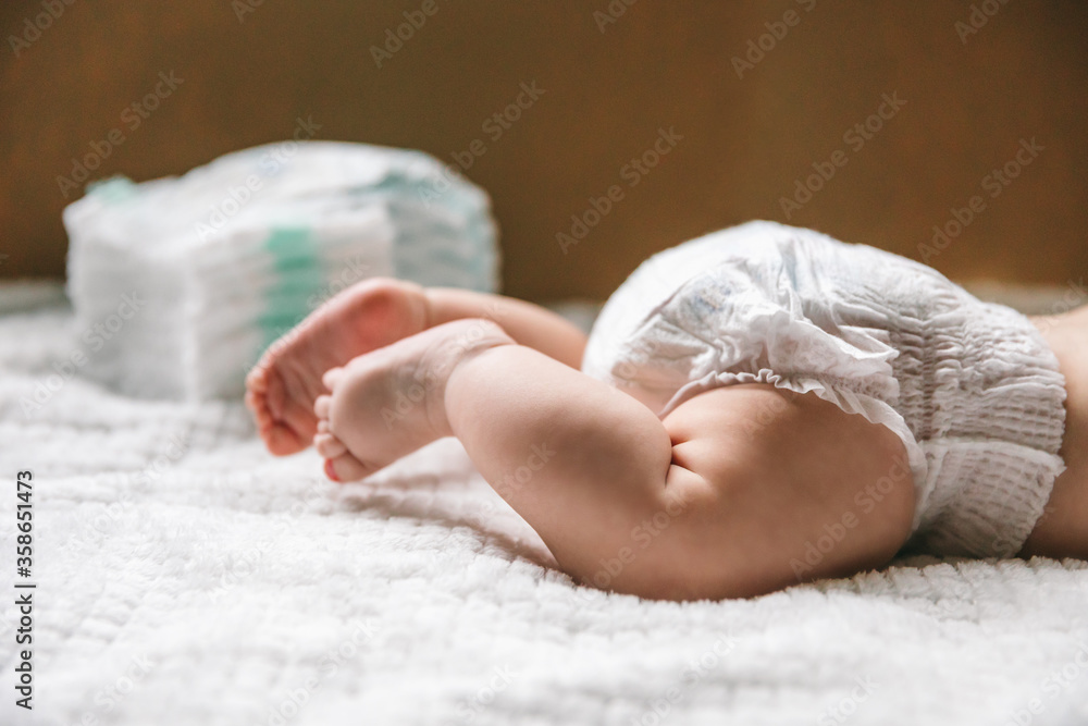 A baby in a diaper at the age of two months and a stack of diapers. How ...