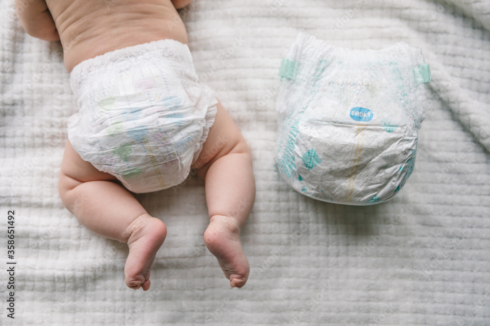 A baby in a diaper at the age of two months and a stack of diapers. How ...