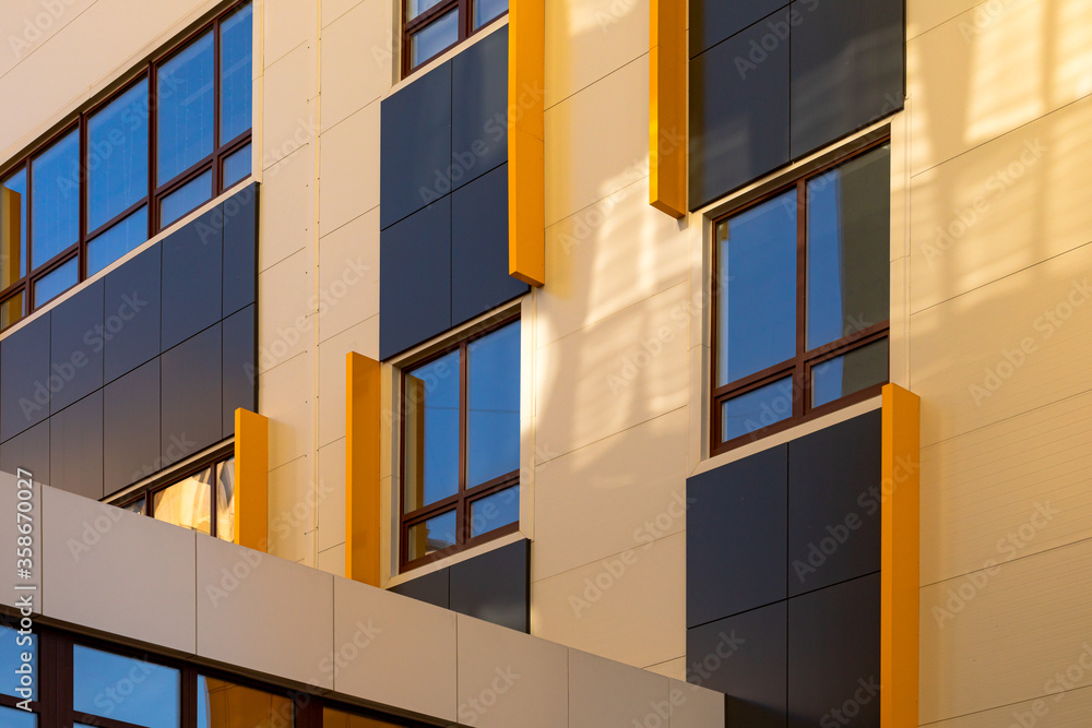 Beige and brown modern ventilated facade with windows. Fragment of a ...
