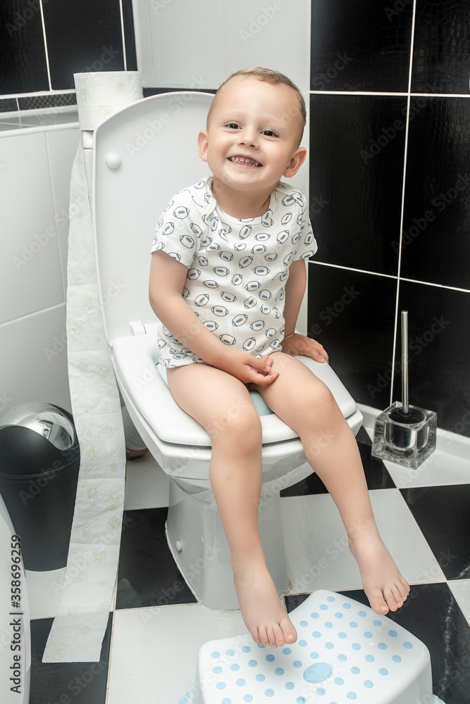 Excited two year old toddler sitting on toilet. Cute kid potty training ...