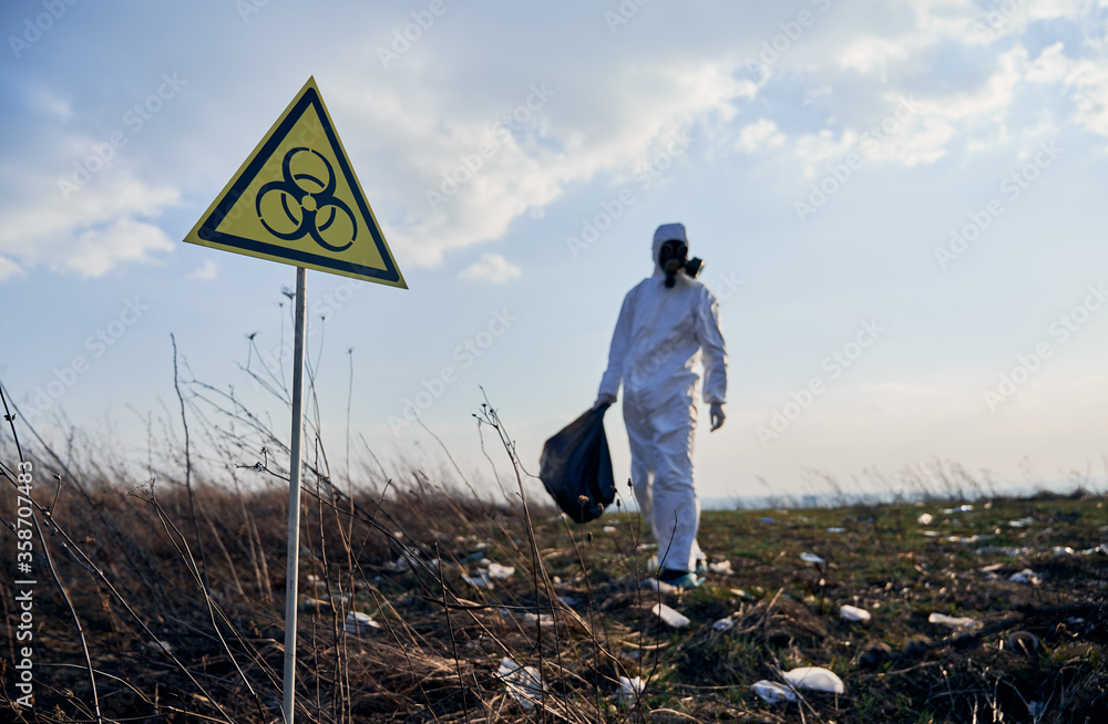 Focus on biohazard warning sign. On blurred background ecologist in ...