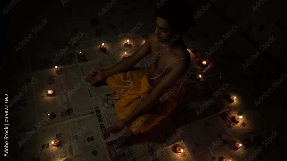 brahmin sadhu between diya(oil lamp) and corona virus news papers ...