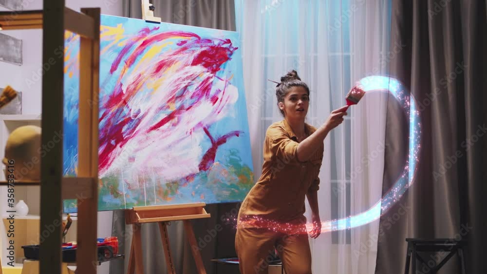 Visionary female artist using mixed reality, drawing with a brush a ...