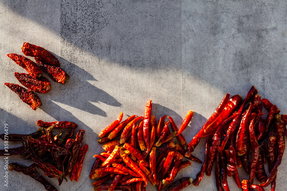Four piles of whole dried chilies against gray table background. Soft ...
