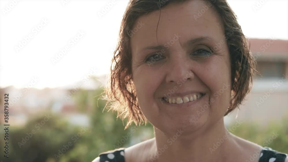 Sympathetic old senior woman is smiling to camera in outdoor with sun ...