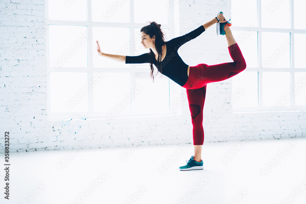 Strong female in active wear standing in pose for training balanse ...