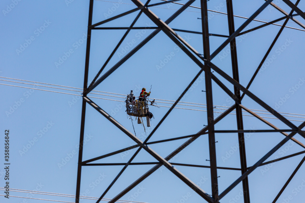Line workers installing spacer dampers on high voltage power conductors ...