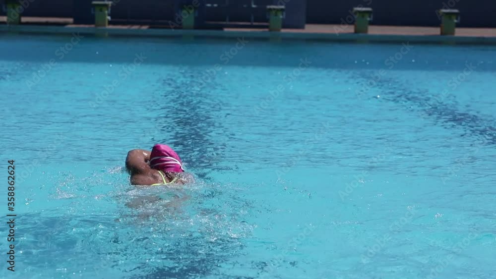 footage of a female swimmer swimming laps in an outdoor pool using the ...