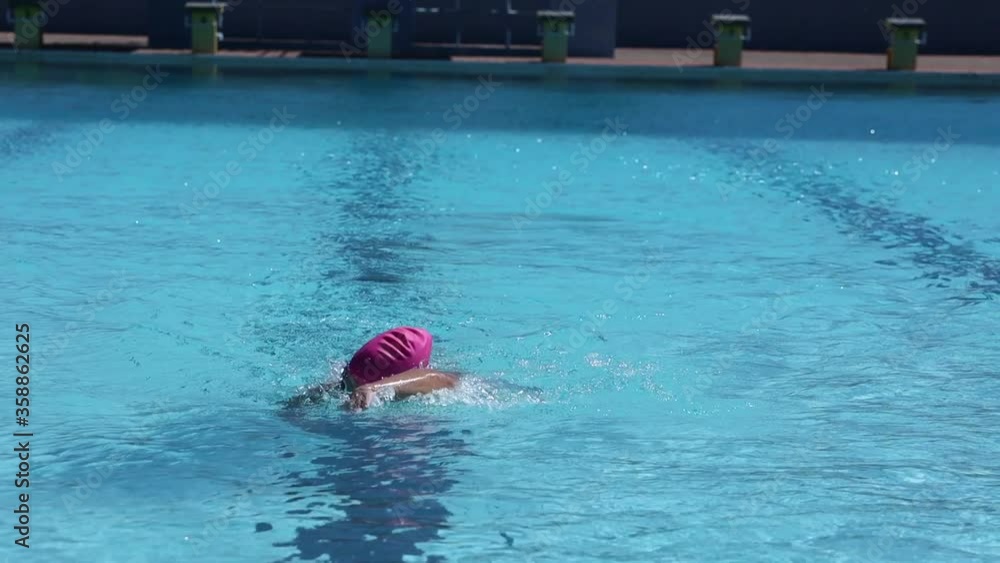 footage of a female swimmer swimming laps in an outdoor pool using the ...