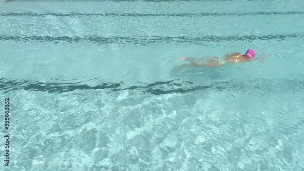 footage of a female swimmer swimming laps in an outdoor pool using the ...