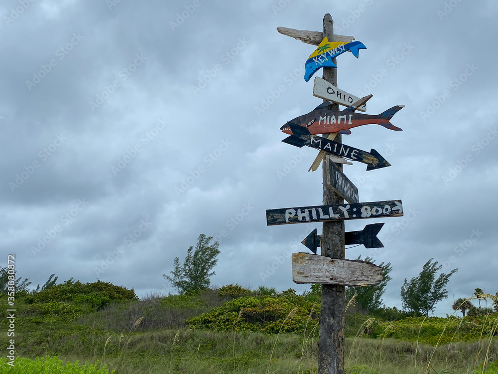 A city directional sign at a beach showing how far cities are from this ...