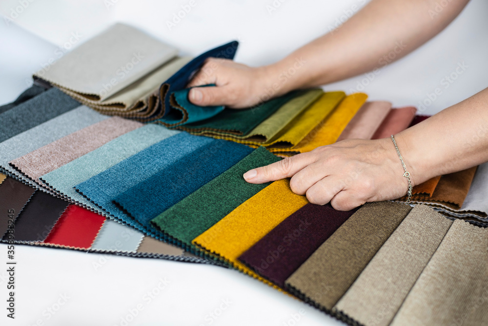 The woman chooses a fabric in the catalog with fabrics with different ...