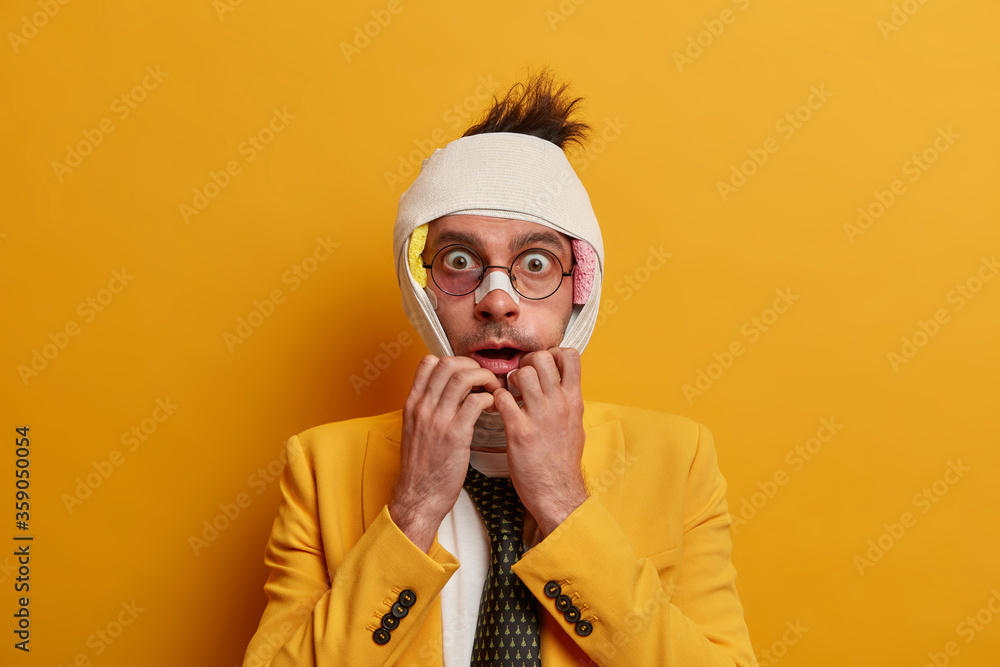Fearful European man looks with scared expression bites finger nails ...