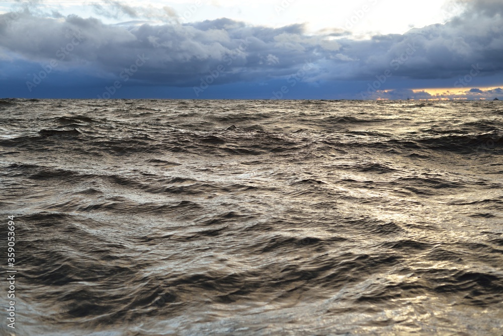A view to the North sea from a sailing boat at sunset. Dramatic stormy ...