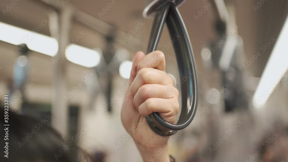 close up Asian woman hand grab on subway train handle, wear black ...