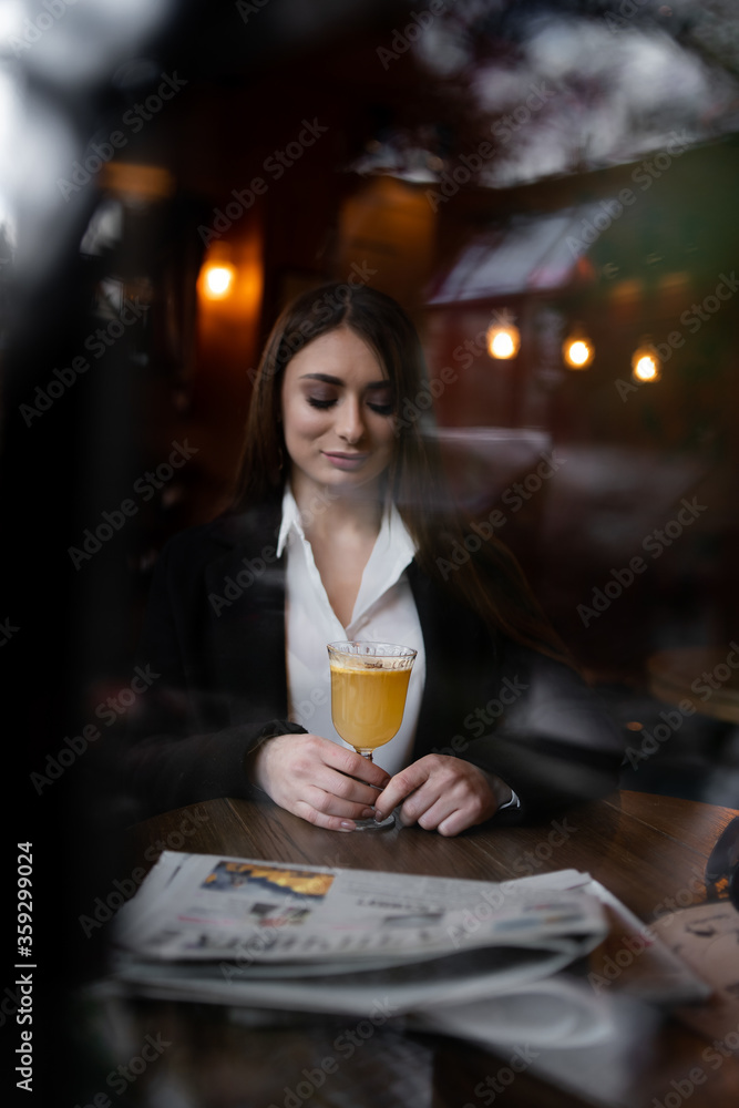 Beautiful brunette girl behind the glass, drinking hot drink portrait ...