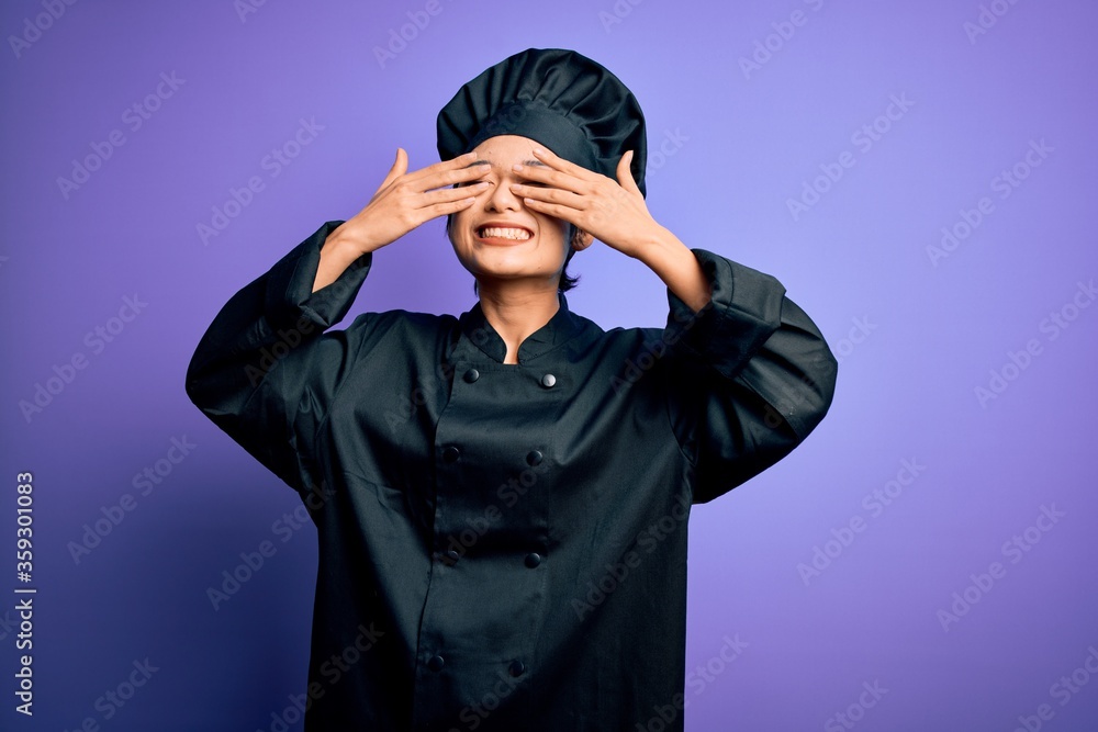Young beautiful chinese chef woman wearing cooker uniform and hat over ...