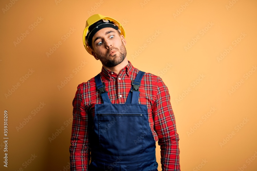 Young builder man wearing construction uniform and safety helmet over ...