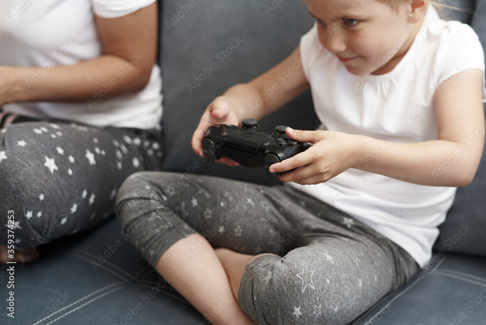 Mother and daughter are playing computer game. A little girl is playing ...