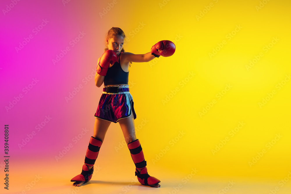 Little caucasian girl, kick boxer on gradient background in neon light ...