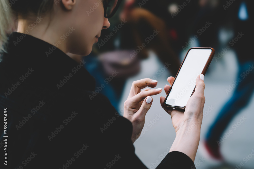 Cropped back view of young woman holding modern smartphone in hands and ...