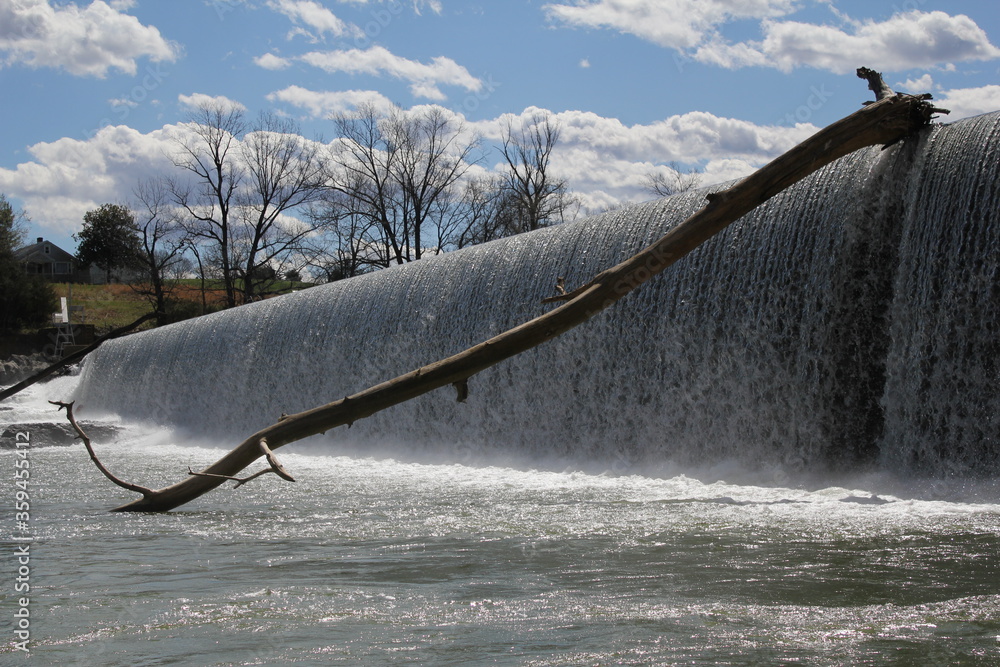hydroelectric dam weir with a fallen tree trunk trapped over the ...