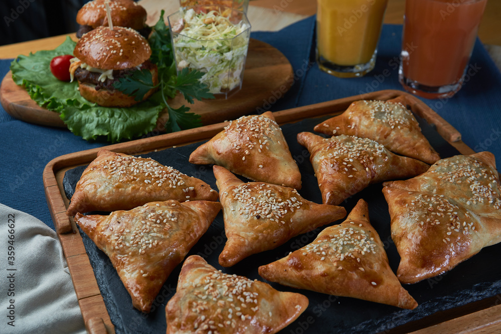 Uzbek dish - mini samosa with sesame seeds on a stone slab. Light ...