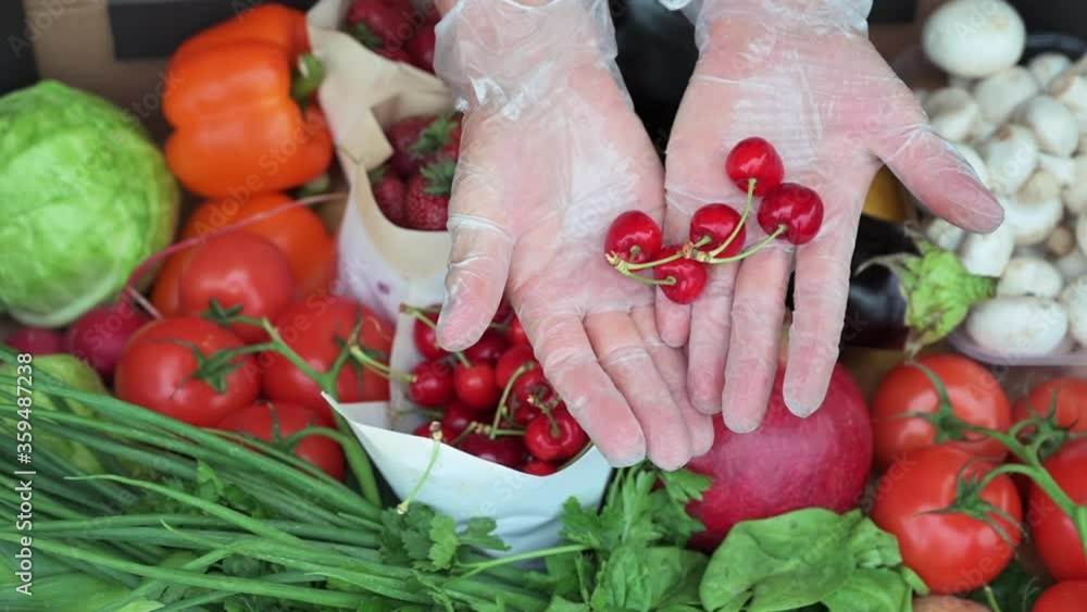 Woman hands with white gloves arranging cherry fruits on a fruits and ...