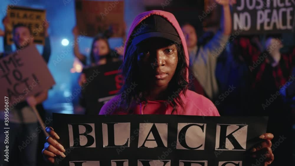 Confident black woman holds invocatory poster, standing in crowd of ...