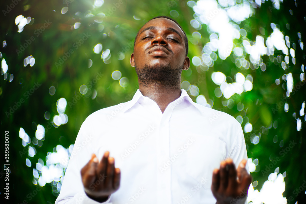 African man praying to god in the green nature.. Stock Photo | Adobe Stock