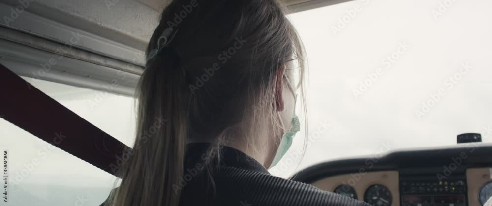 Woman copilot with face mask excited in cockpit of small airplane plane ...