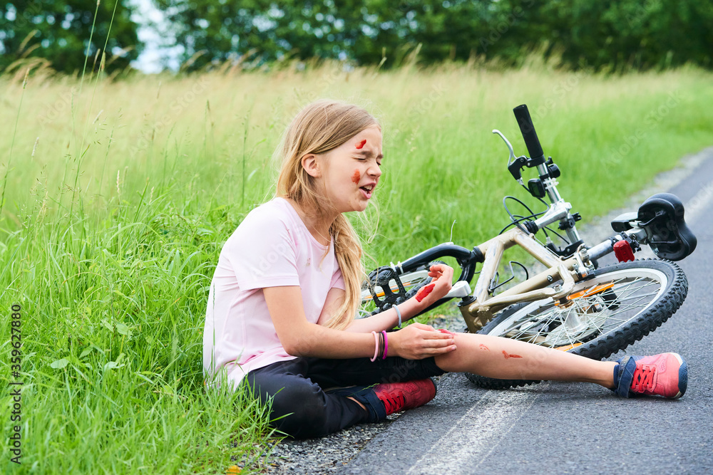 Foto de Sad crying little child girl fell from the bike in the summer ...