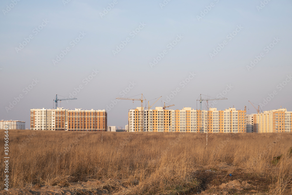 Multi-story complex of houses, construction is underway, cranes are ...