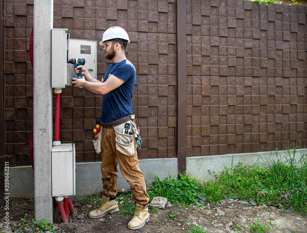 Electrician Builder at work, examines the cable connection in the ...