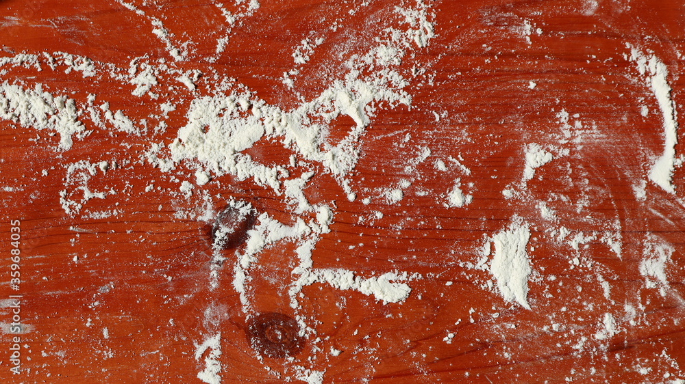 bright wooden red background with stains of dry sprinkled white flour ...