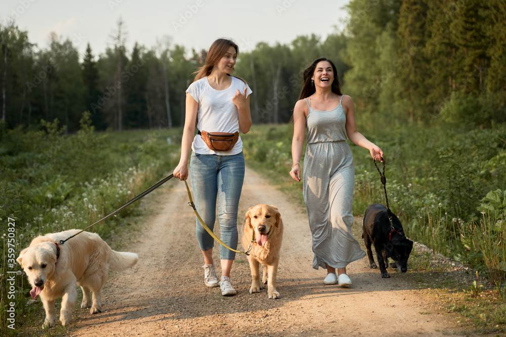 Two happy women on walk with three dogs in park Stock Photo | Adobe Stock