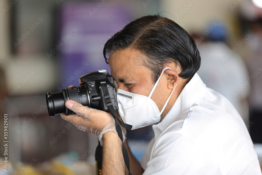 Photographer at work during Covid-19 pandemic. Photographer in mask and ...