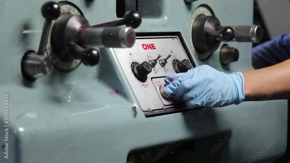 Machine operator activates huge commercial printing press in shop to ...