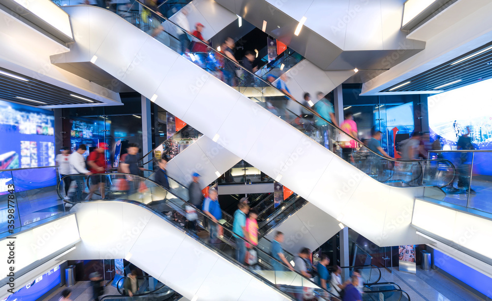 Customers clients moving on escalator staircases inside of giant modern shopping mall ...