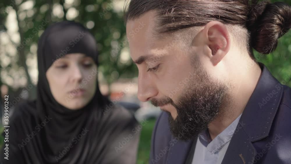 Close-up side view of tired bearded Middle Eastern man sighing as ...