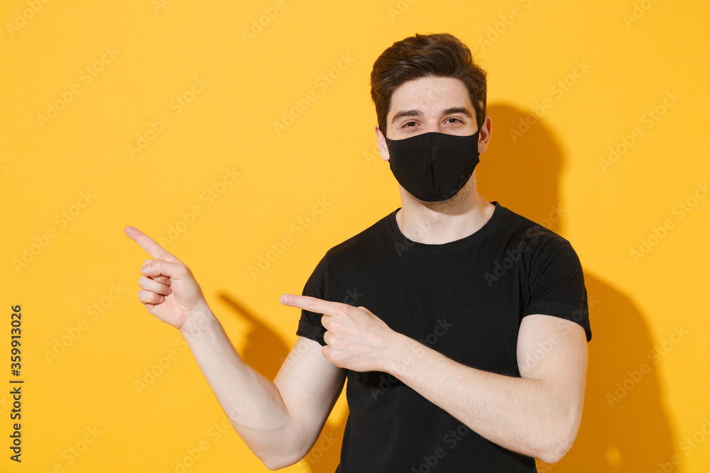 Smiling young man guy in black t-shirt face mask isolated on yellow ...