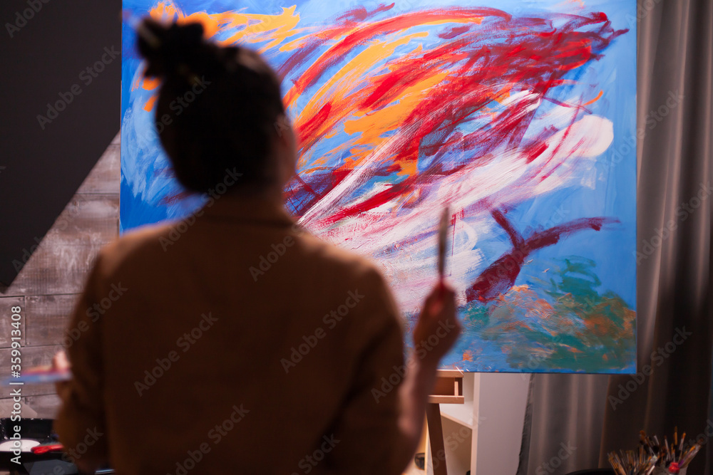 Painter in art workshop looking at painting composition in art studio ...